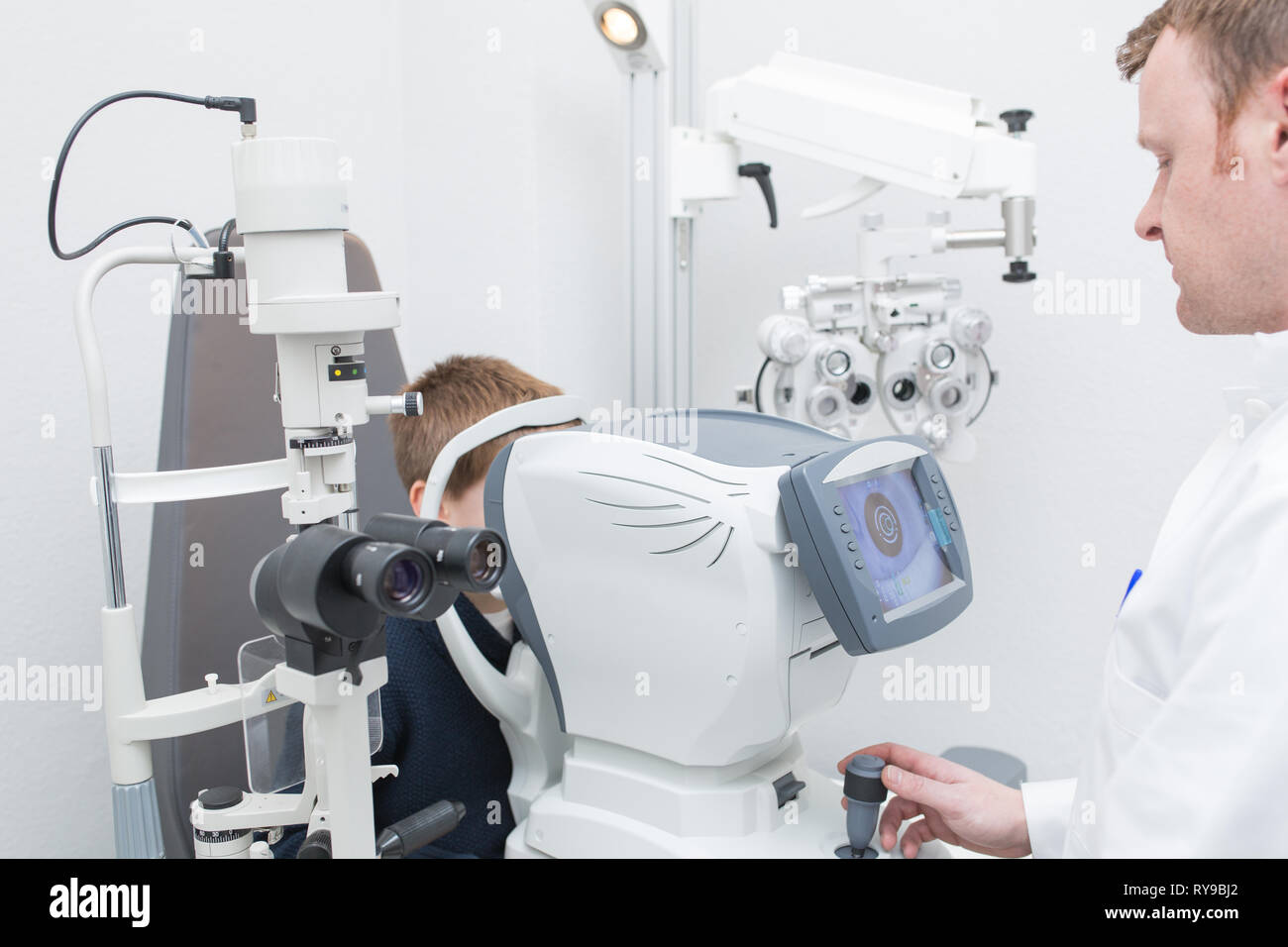 Optician testing a boy's eyes with optometry devices Stock Photo - Alamy