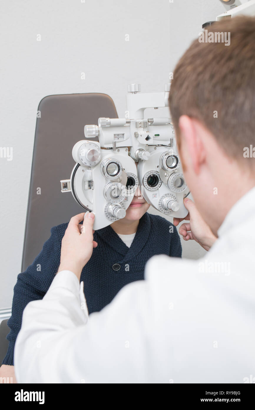 Optician testing a boy's eyes with optometry devices Stock Photo - Alamy