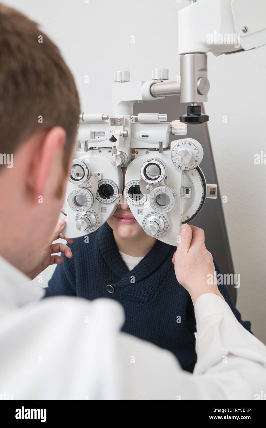 Optician testing a boy's eyes with optometry devices Stock Photo - Alamy