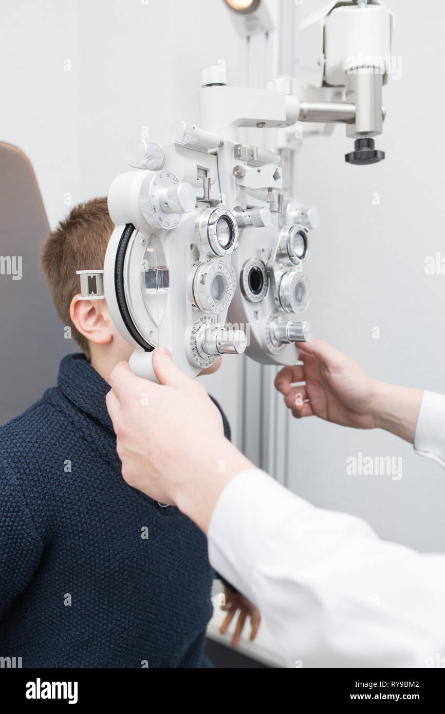 Optician testing a boy's eyes with optometry devices Stock Photo - Alamy