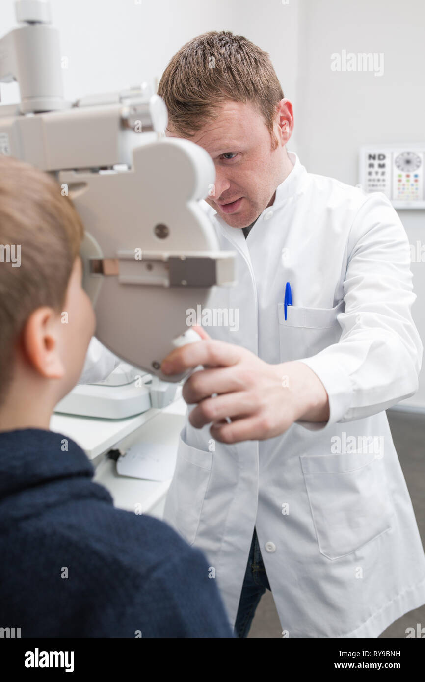 Optician testing a boy's eyes with optometry devices Stock Photo - Alamy