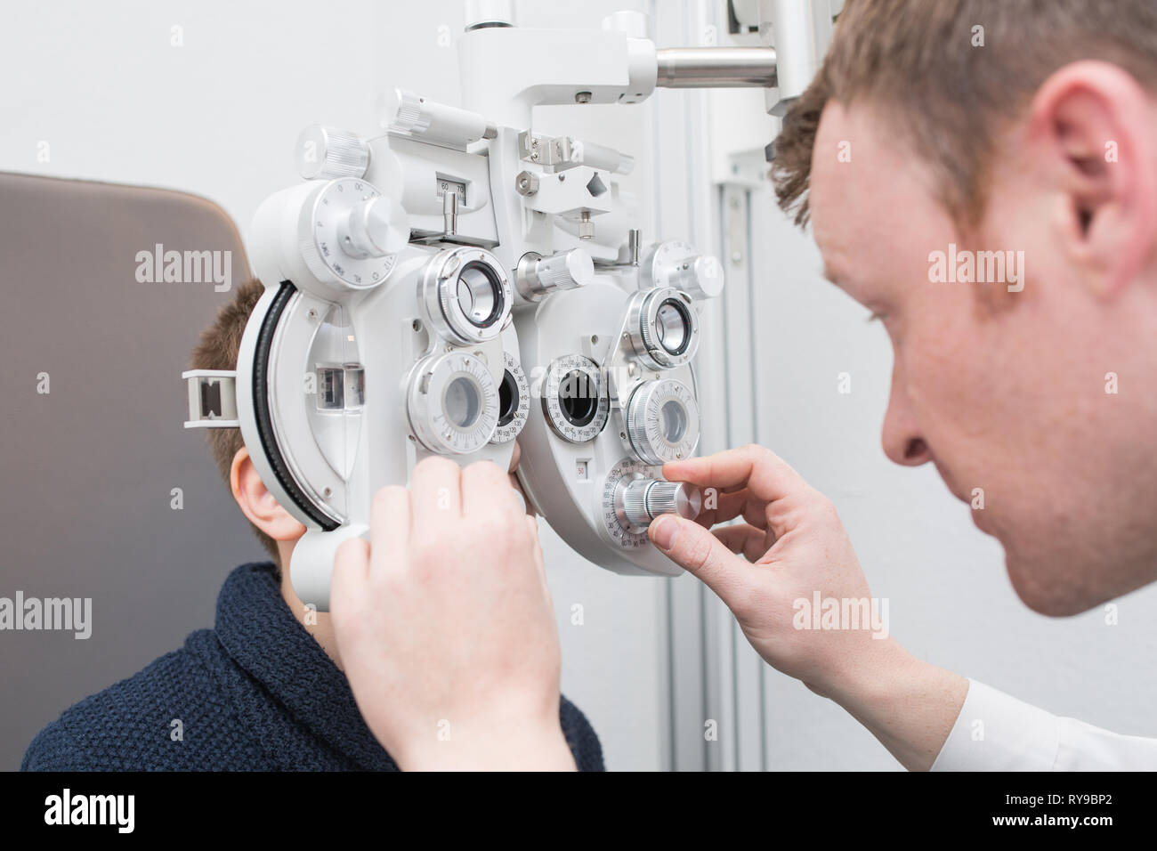 Optician testing a boy's eyes with optometry devices Stock Photo - Alamy
