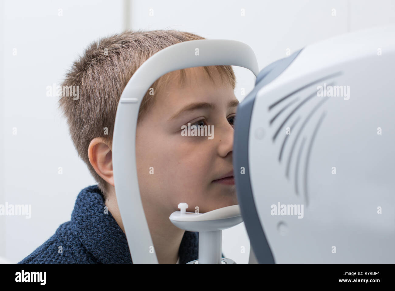 Optician testing a boy's eyes with optometry devices Stock Photo - Alamy