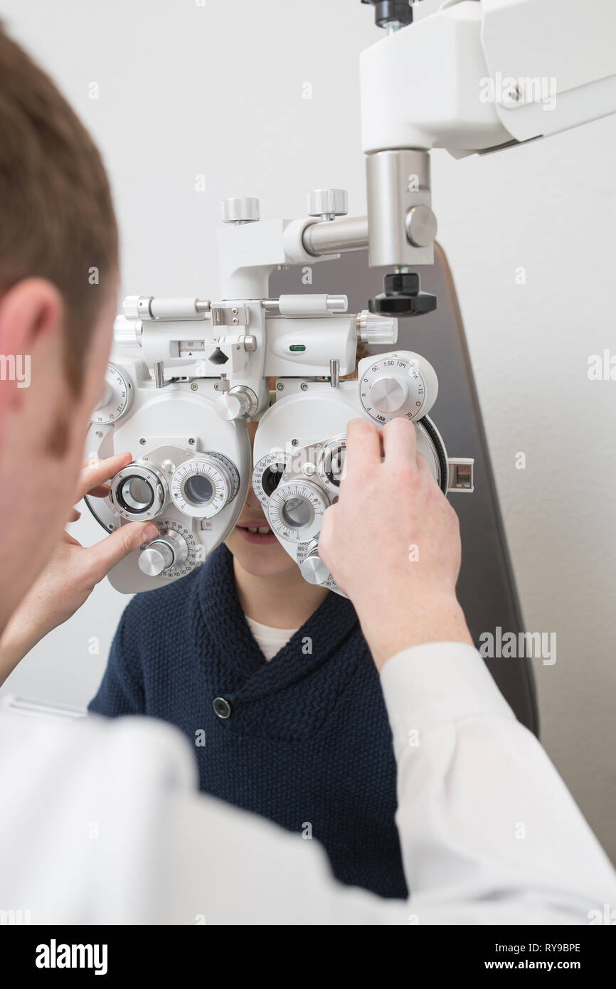Optician testing a boy's eyes with optometry devices Stock Photo - Alamy