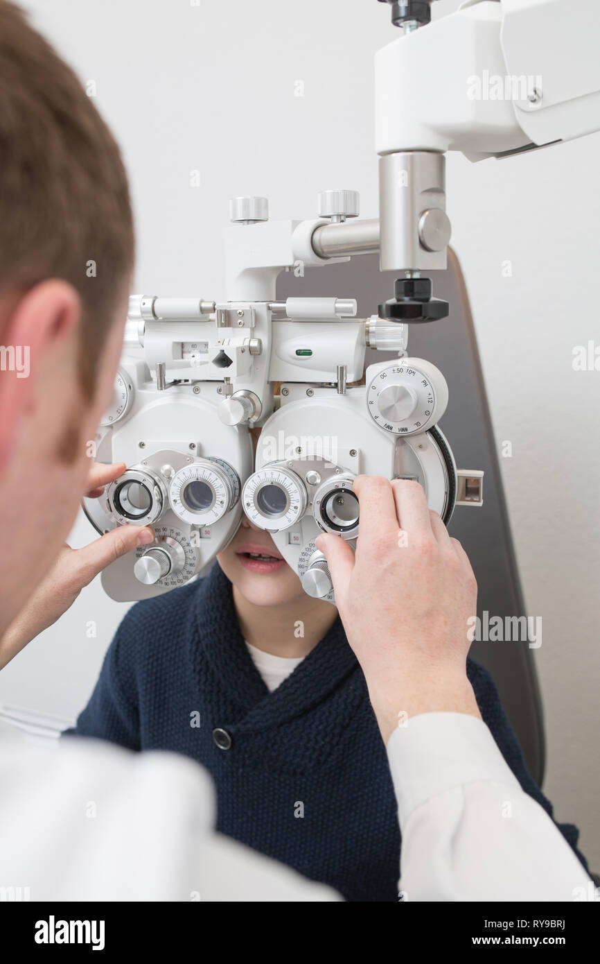 Optician testing a boy's eyes with optometry devices Stock Photo - Alamy