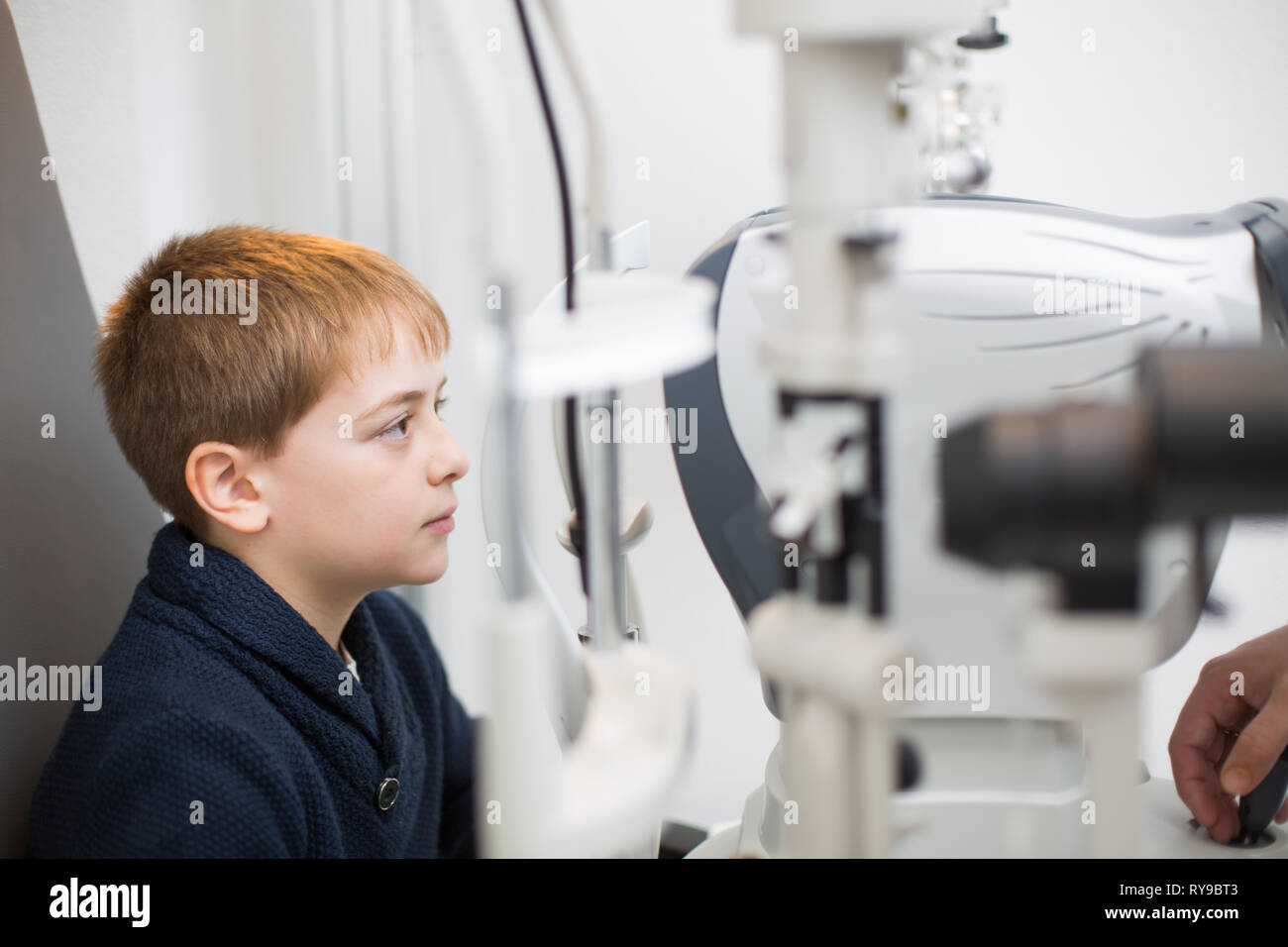 Optician testing a boy's eyes with optometry devices Stock Photo - Alamy