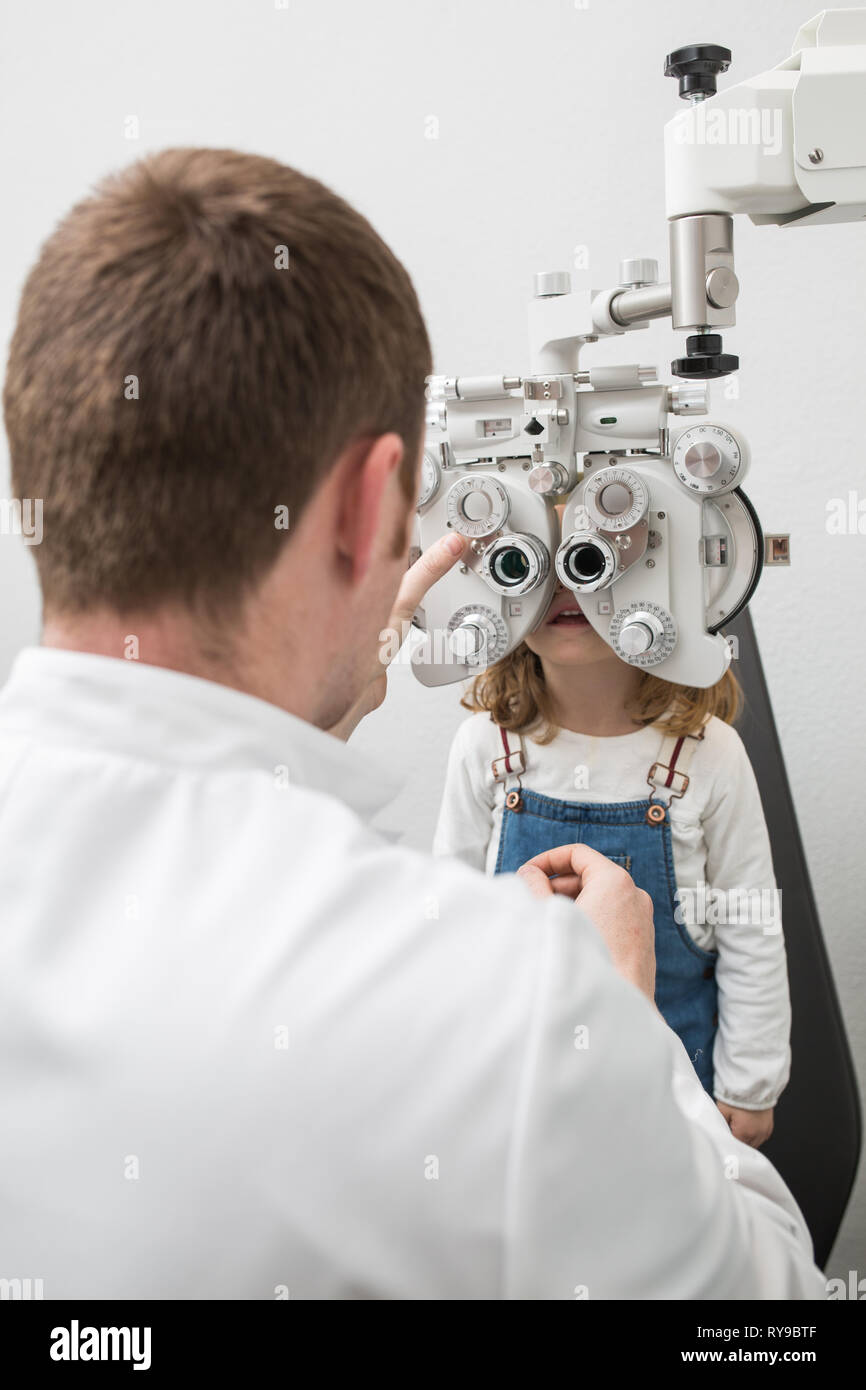 Optician testing a girl's eyes with optometry devices Stock Photo - Alamy