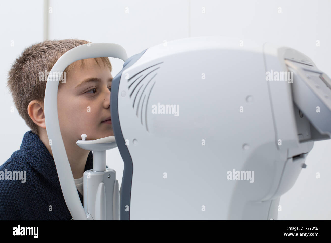 Optician testing a boy's eyes with optometry devices Stock Photo - Alamy
