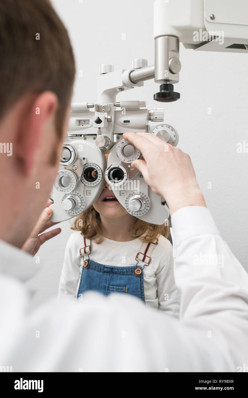 Optician testing a girl's eyes with optometry devices Stock Photo - Alamy