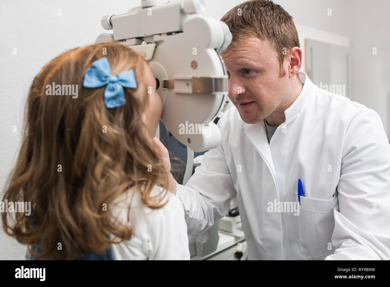 Optician testing a girl's eyes with optometry devices Stock Photo - Alamy