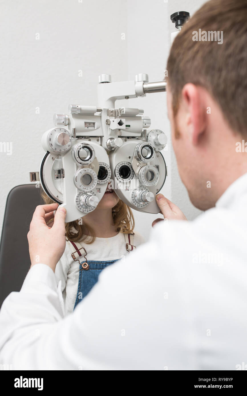 Optician testing a girl's eyes with optometry devices Stock Photo - Alamy