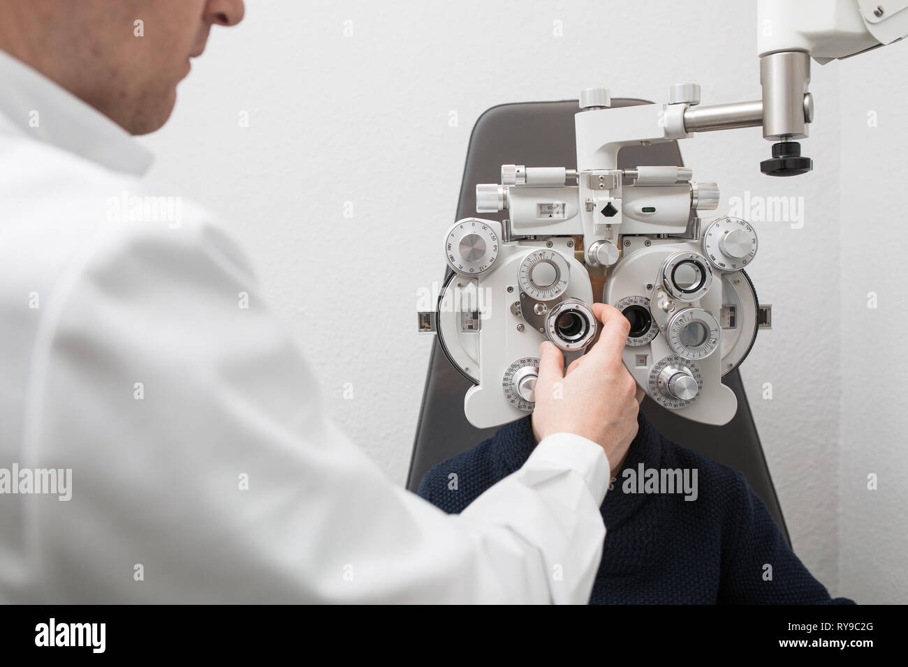 Optician testing a boy's eyes with optometry devices Stock Photo - Alamy