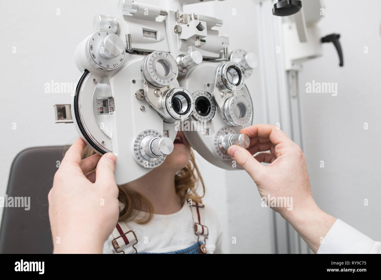 Optician testing a girl's eyes with optometry devices Stock Photo - Alamy