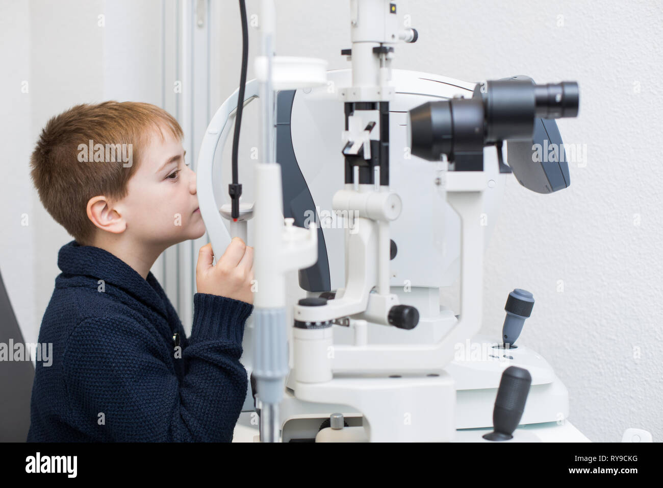 Optician testing a boy's eyes with optometry devices Stock Photo - Alamy