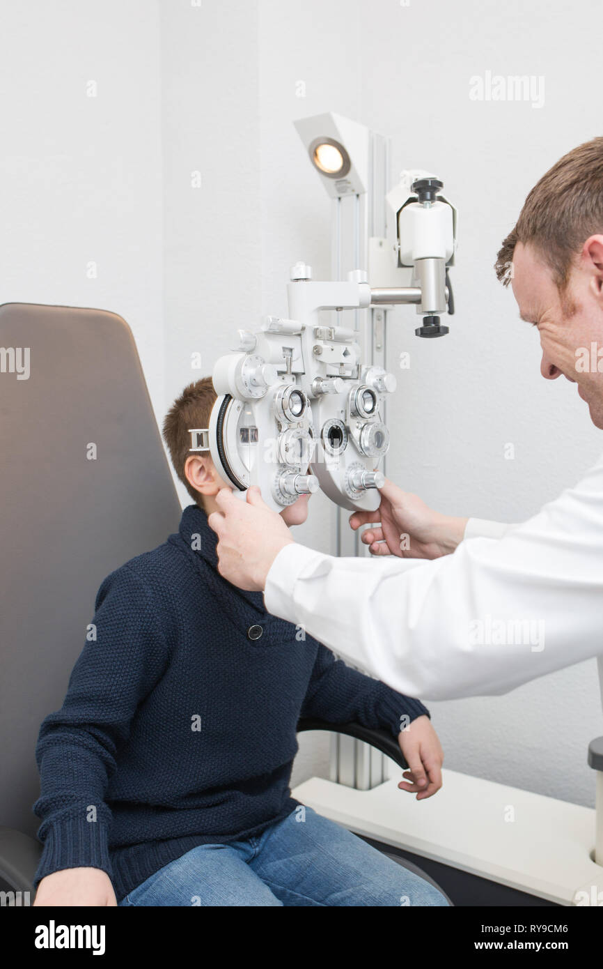 Optician testing a boy's eyes with optometry devices Stock Photo - Alamy