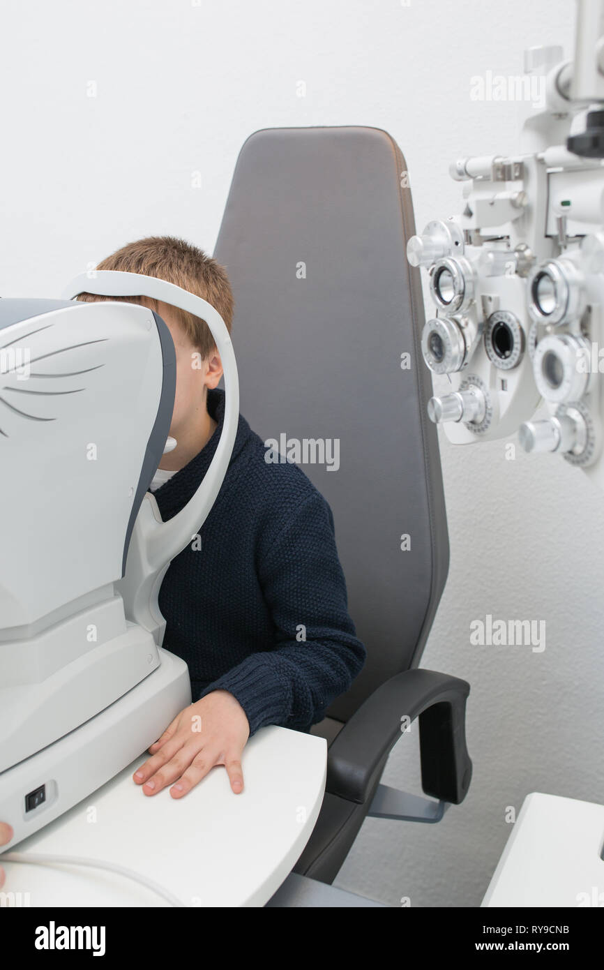 Optician testing a boy's eyes with optometry devices Stock Photo - Alamy