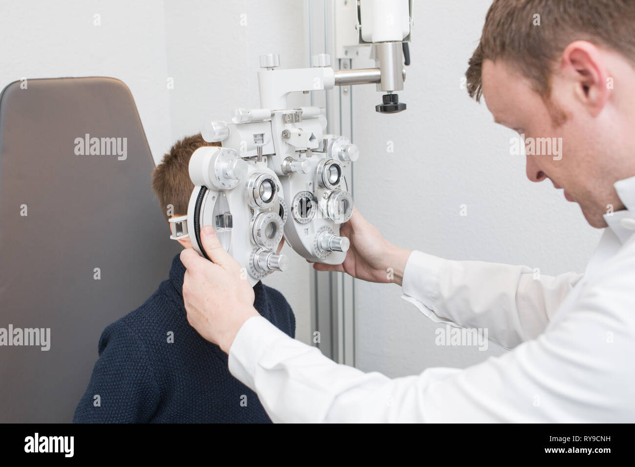 Optician testing a boy's eyes with optometry devices Stock Photo - Alamy