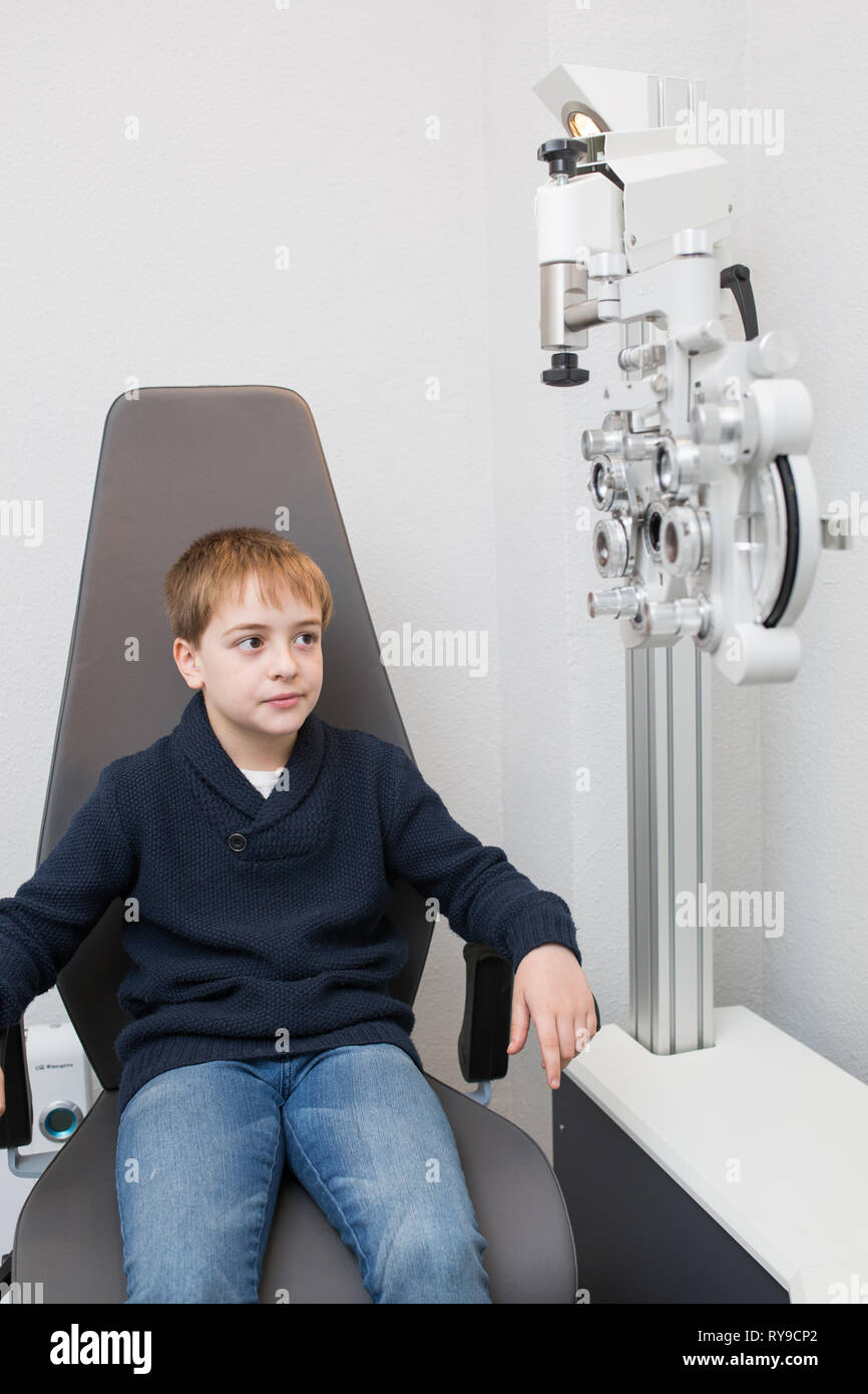 Optician testing a boy's eyes with optometry devices Stock Photo - Alamy