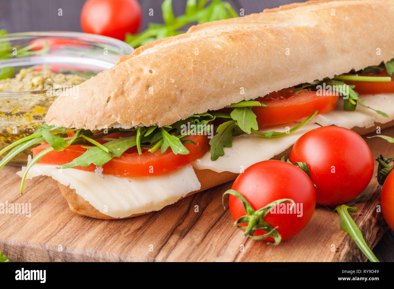 Toasted panini with ham, cheese and arugula sandwich on cutting board ...