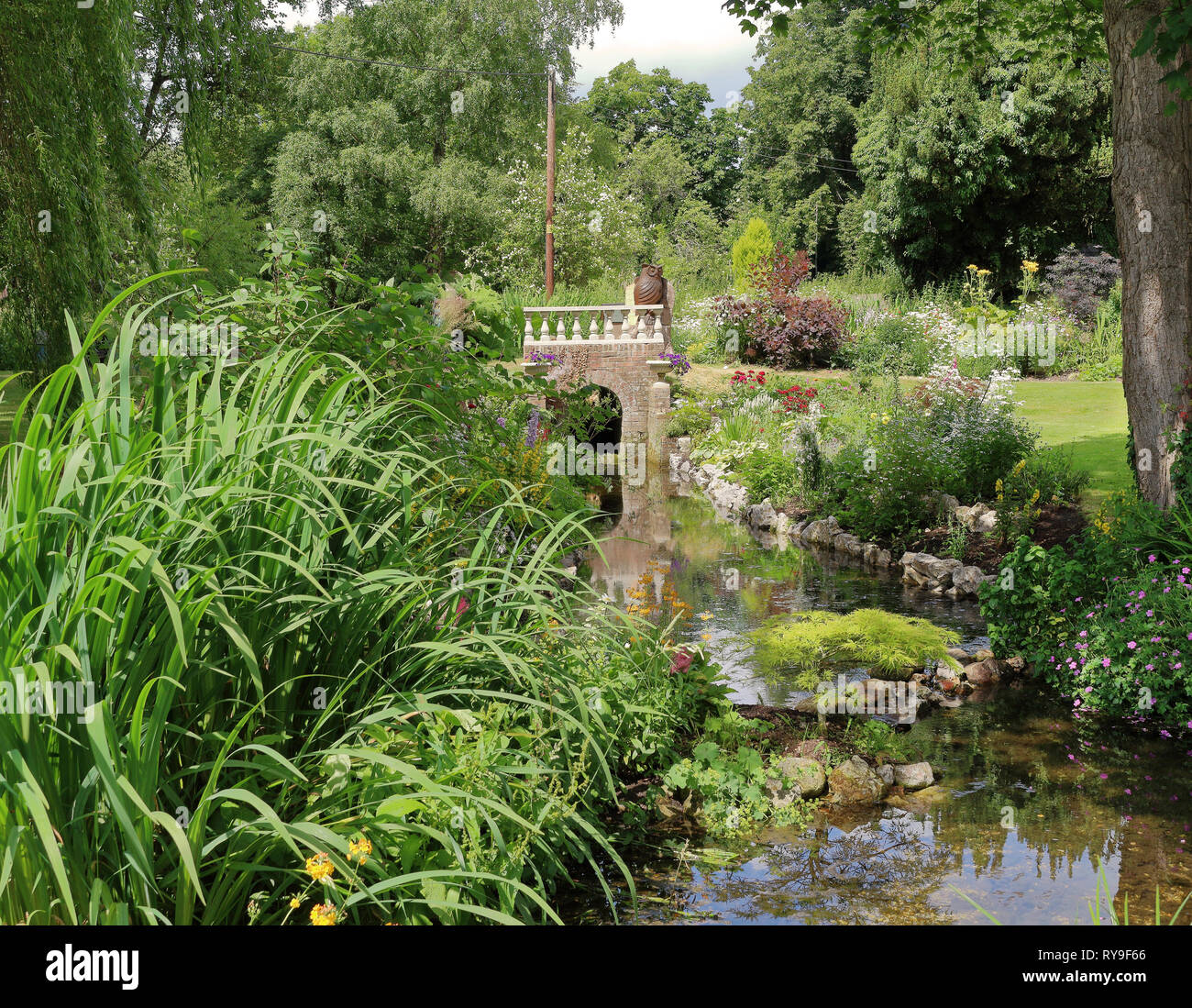 Lush English Garden with stream and small stone footbridge Stock Photo ...