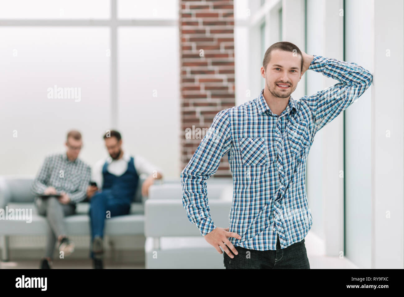 smiling young employee standing in the office Stock Photo - Alamy