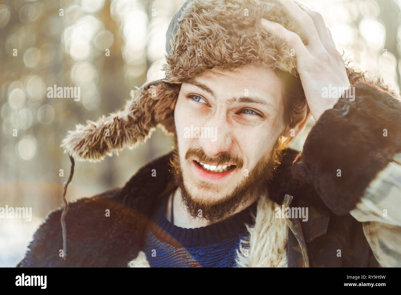 Siberian Russian man in a hat with earflaps and a log Stock Photo - Alamy