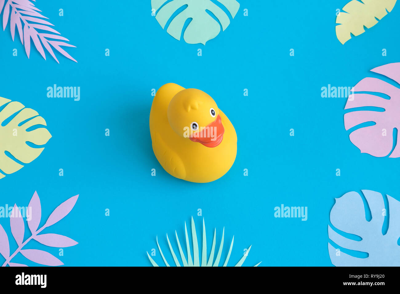 Rubber duck with colorful tropical leaves against pastel blue ...