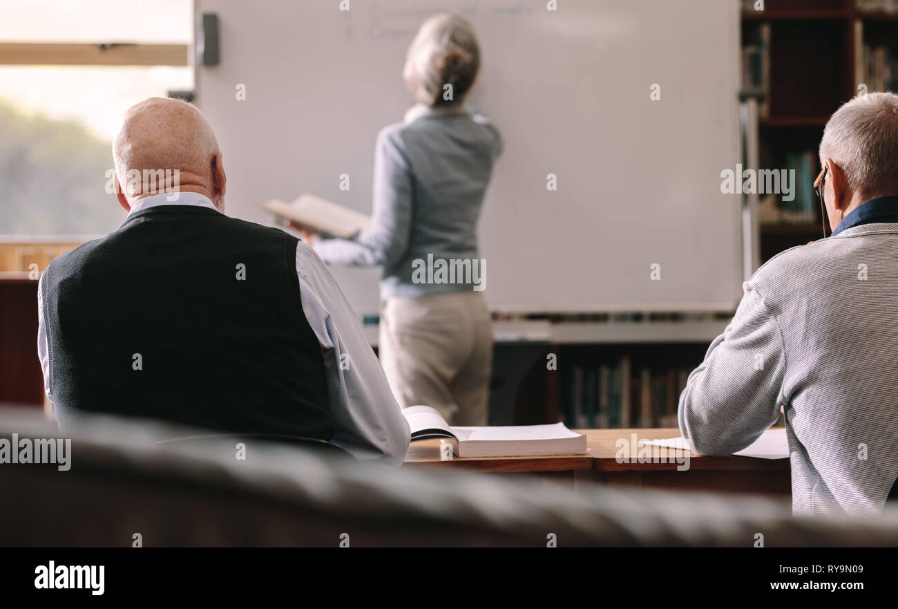 Senior men attending a lecture in a classroom. Rear view of senior ...
