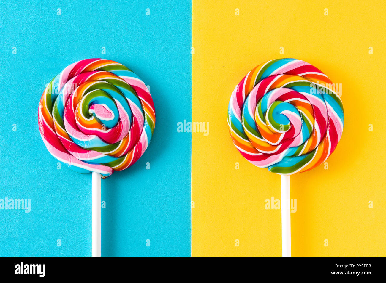 Colorful lollipops on blue and yellow background Stock Photo - Alamy