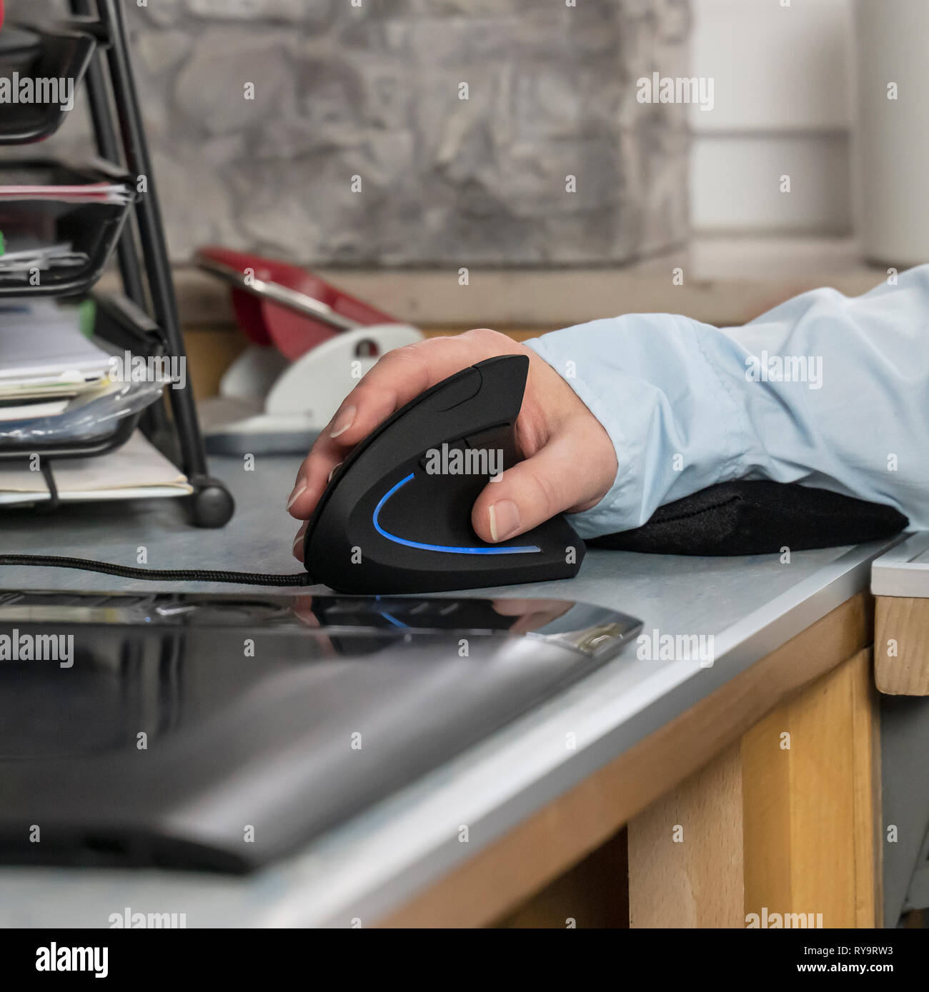 A workplace with a computer. On the desk is a hand in relief position ...