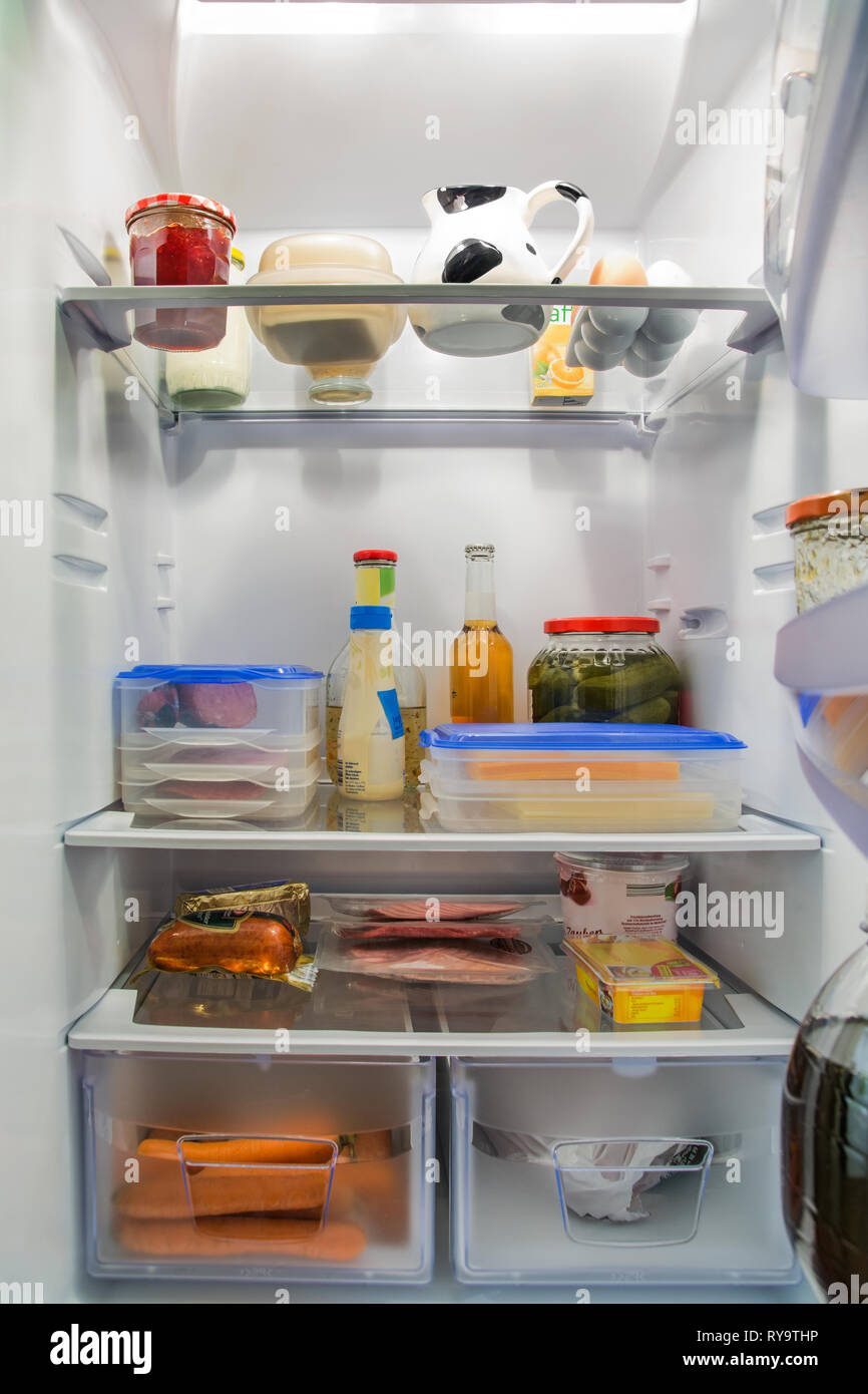 A big white fridge is filled with lots of food. Sausage, cheese, milk ...