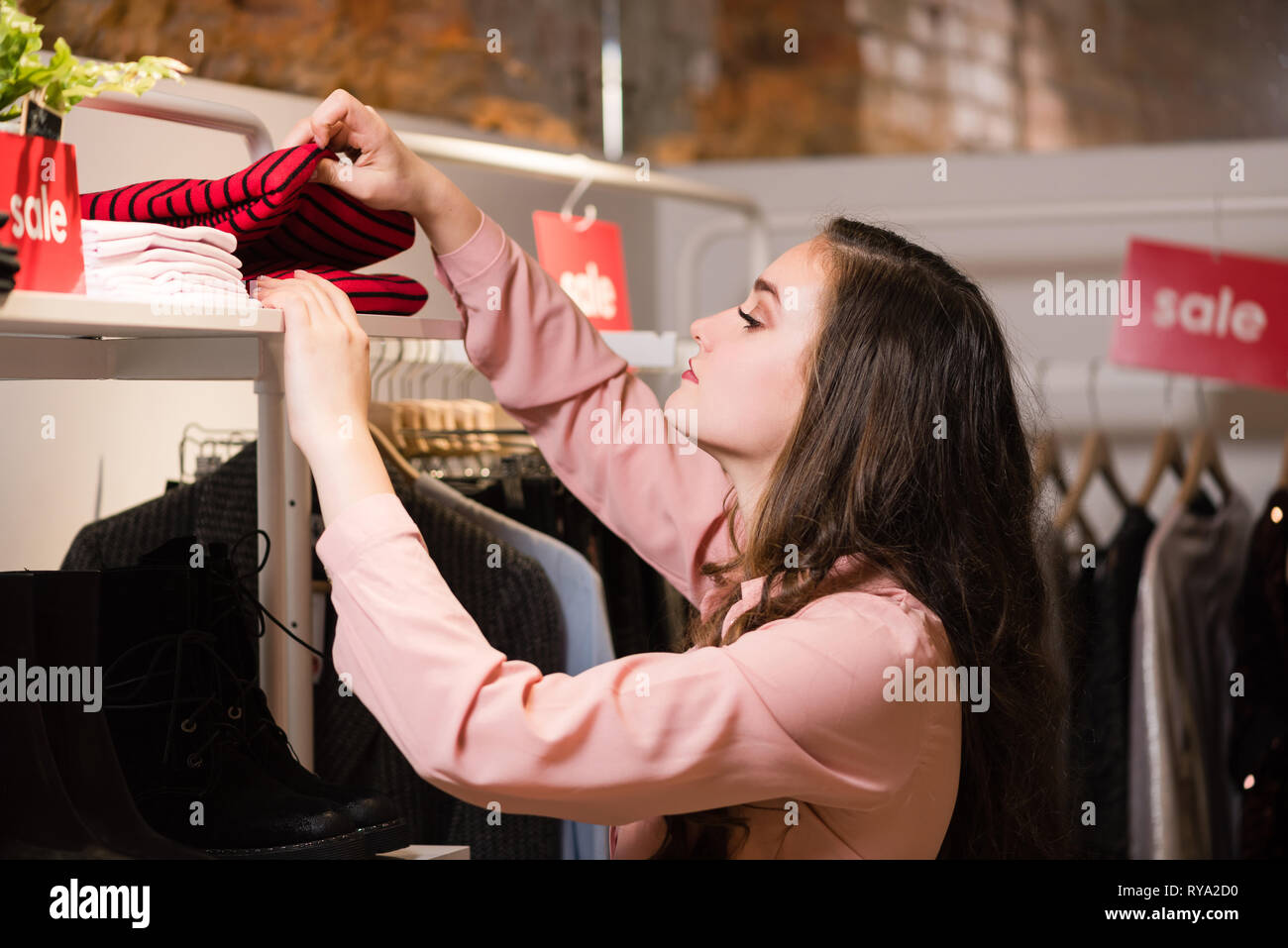 Woman folds clothes neatly on store rack close up Stock Photo - Alamy