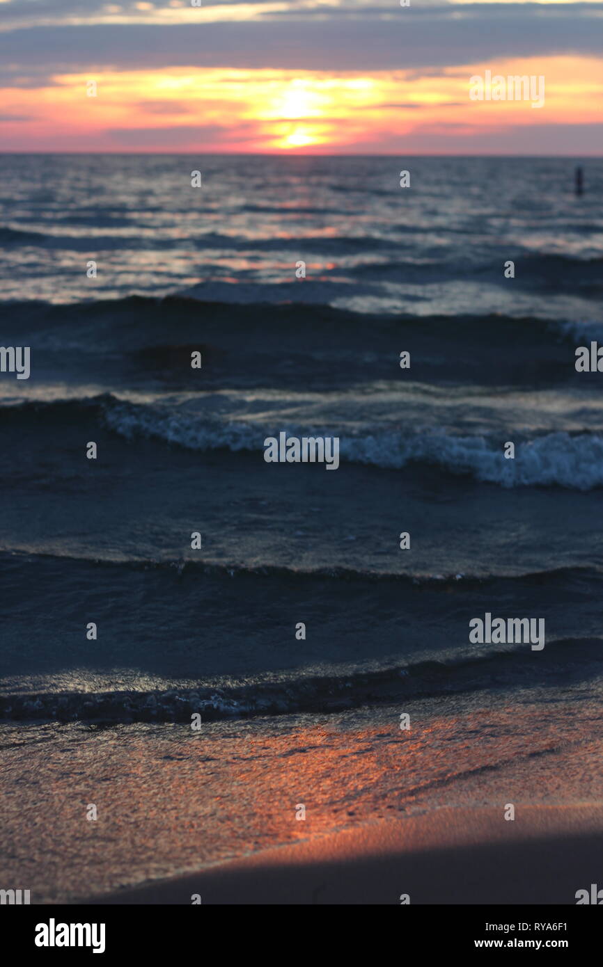 Lake Michigan at sunset. orange sun setting, toes in the sand Stock ...