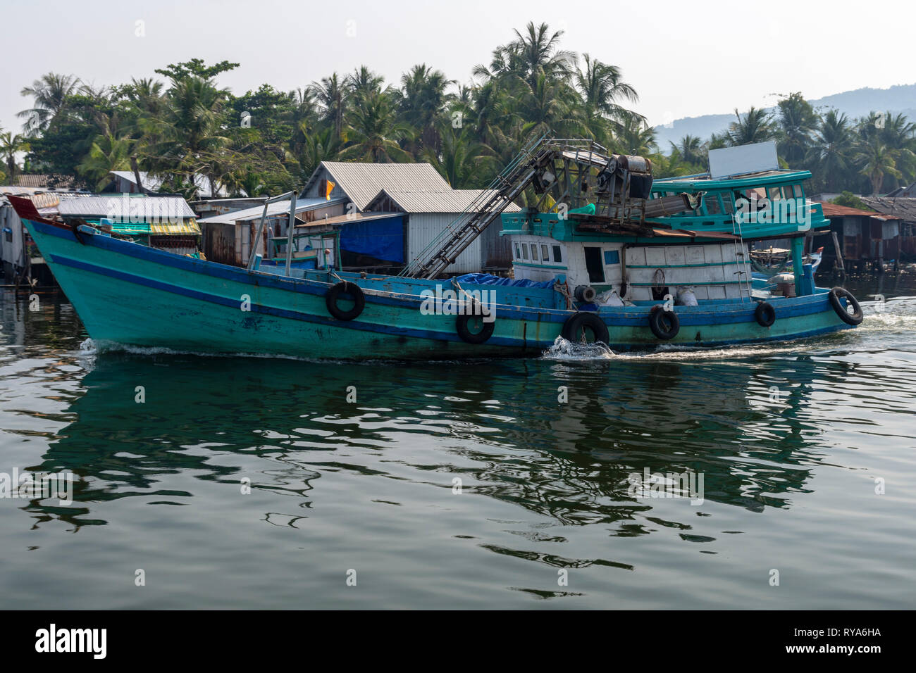 Fishing boat on the Duong Dong river and fishing huts and palm trees in ...