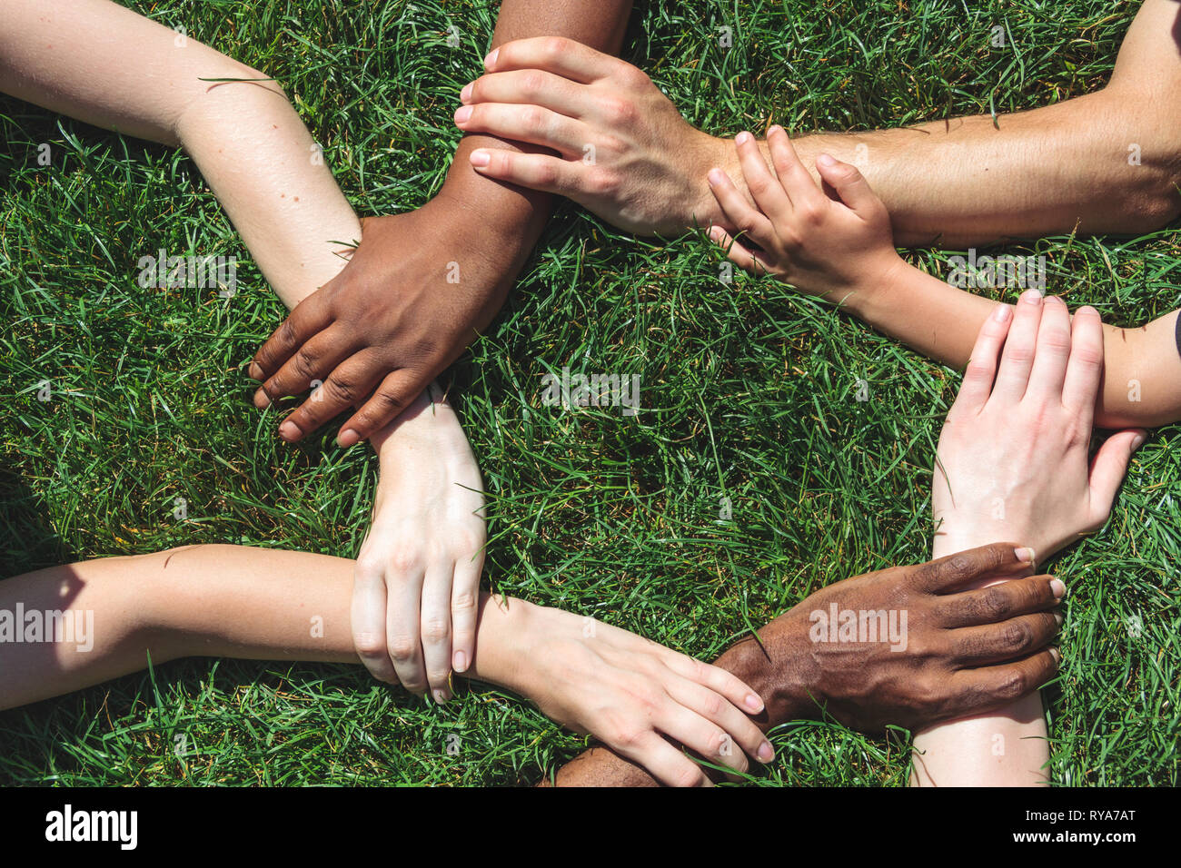 Multiethnic group forming a circle of hands on the ground. A child hand ...