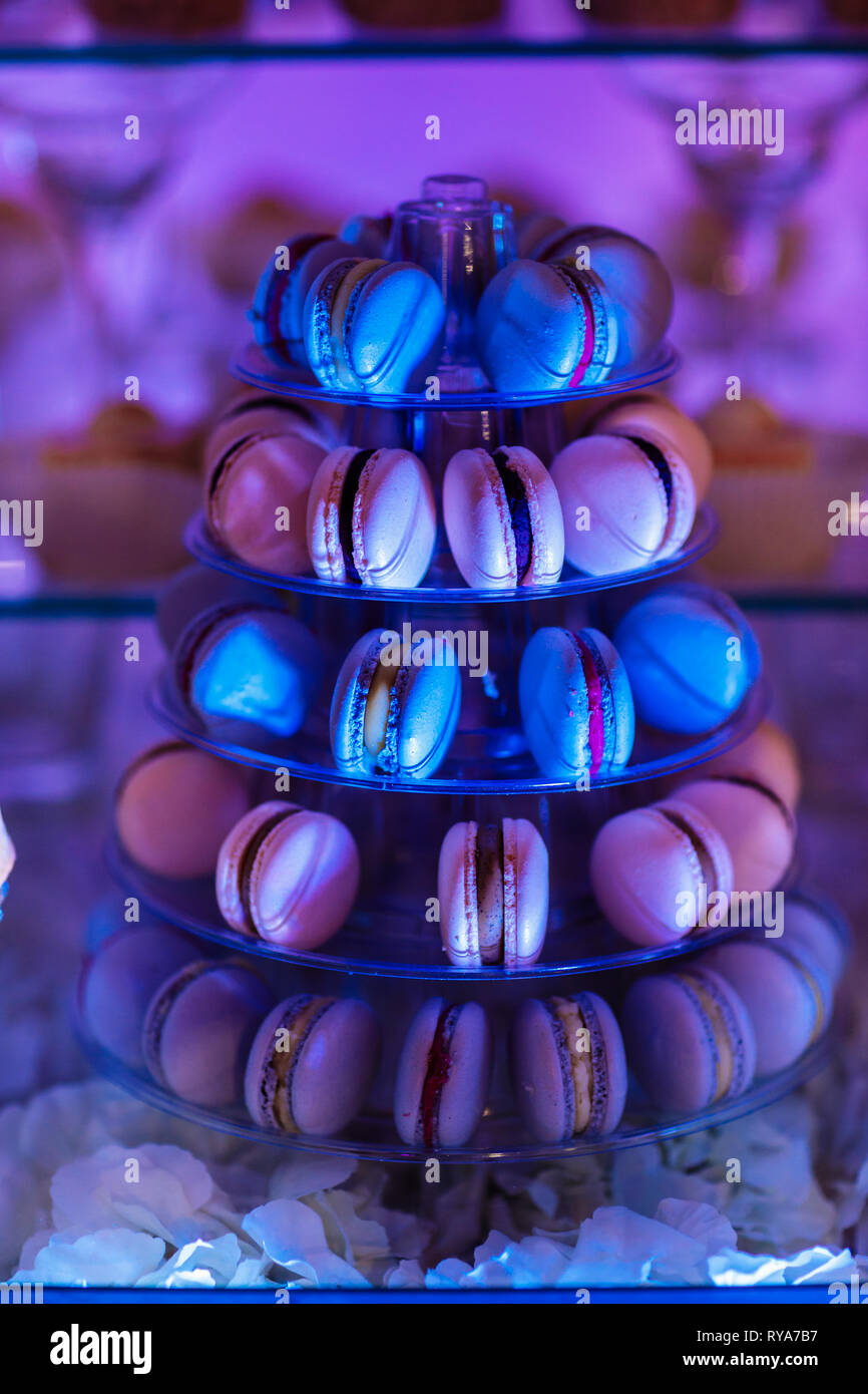 Colorful macarons stand in round transparent weight as part of candy ...