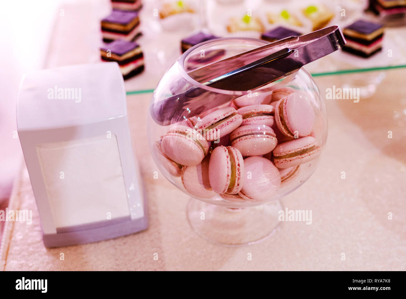 Colorful macarons stand in round transparent weight as part of candy ...