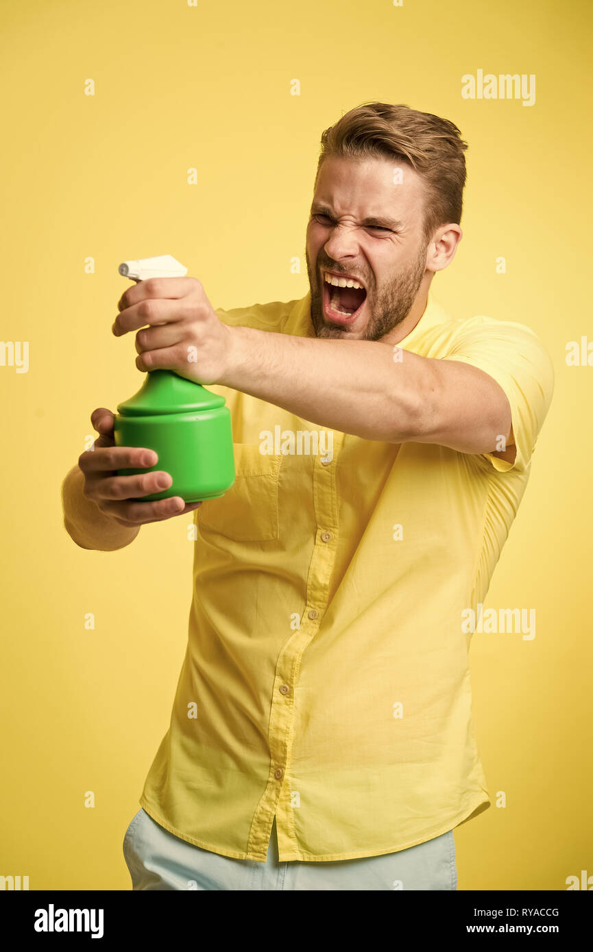 Macho hold plastic spray bottle as gun yellow background. Guy with ...