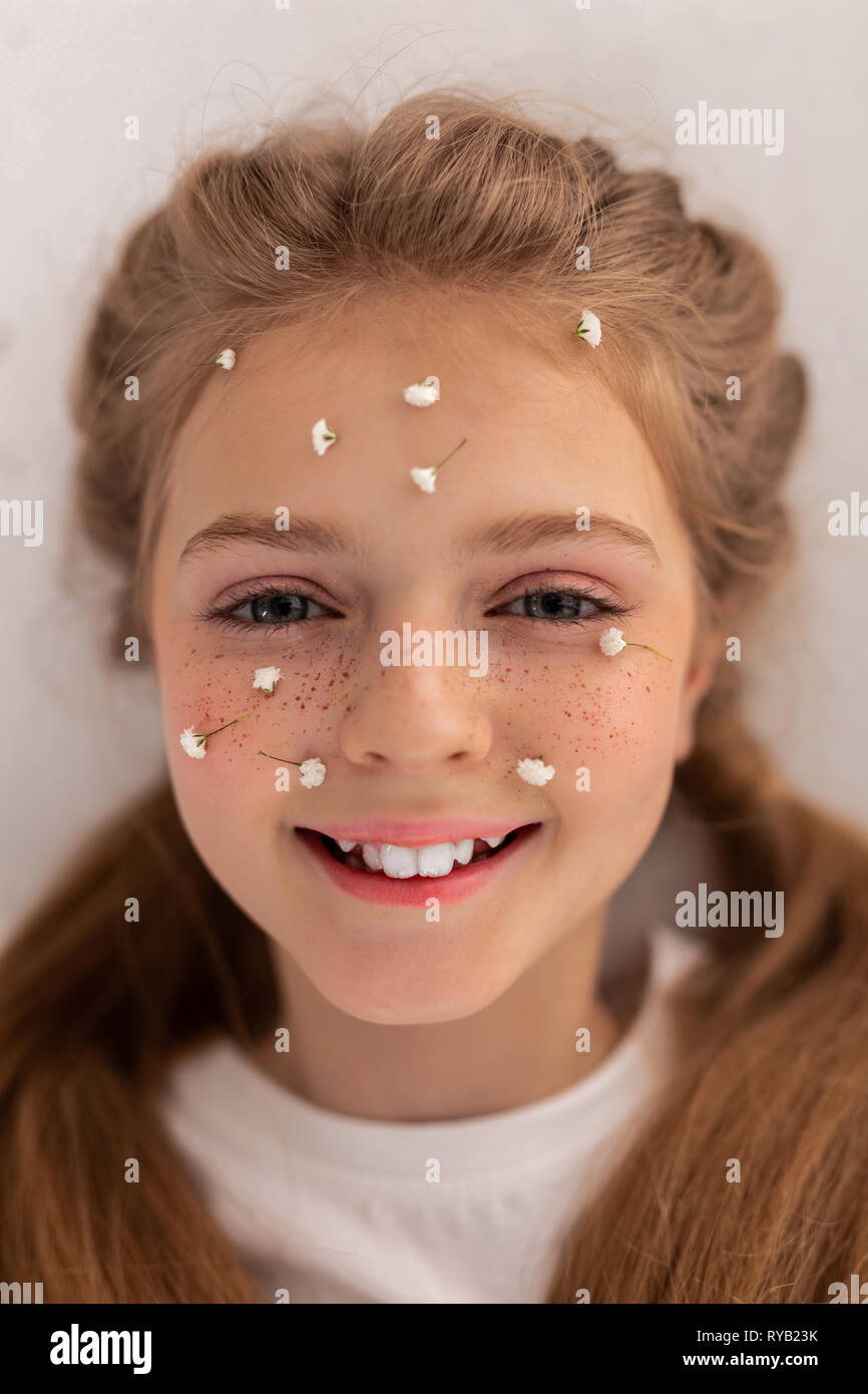 Contented little child with wide smile having flowers all over her face ...