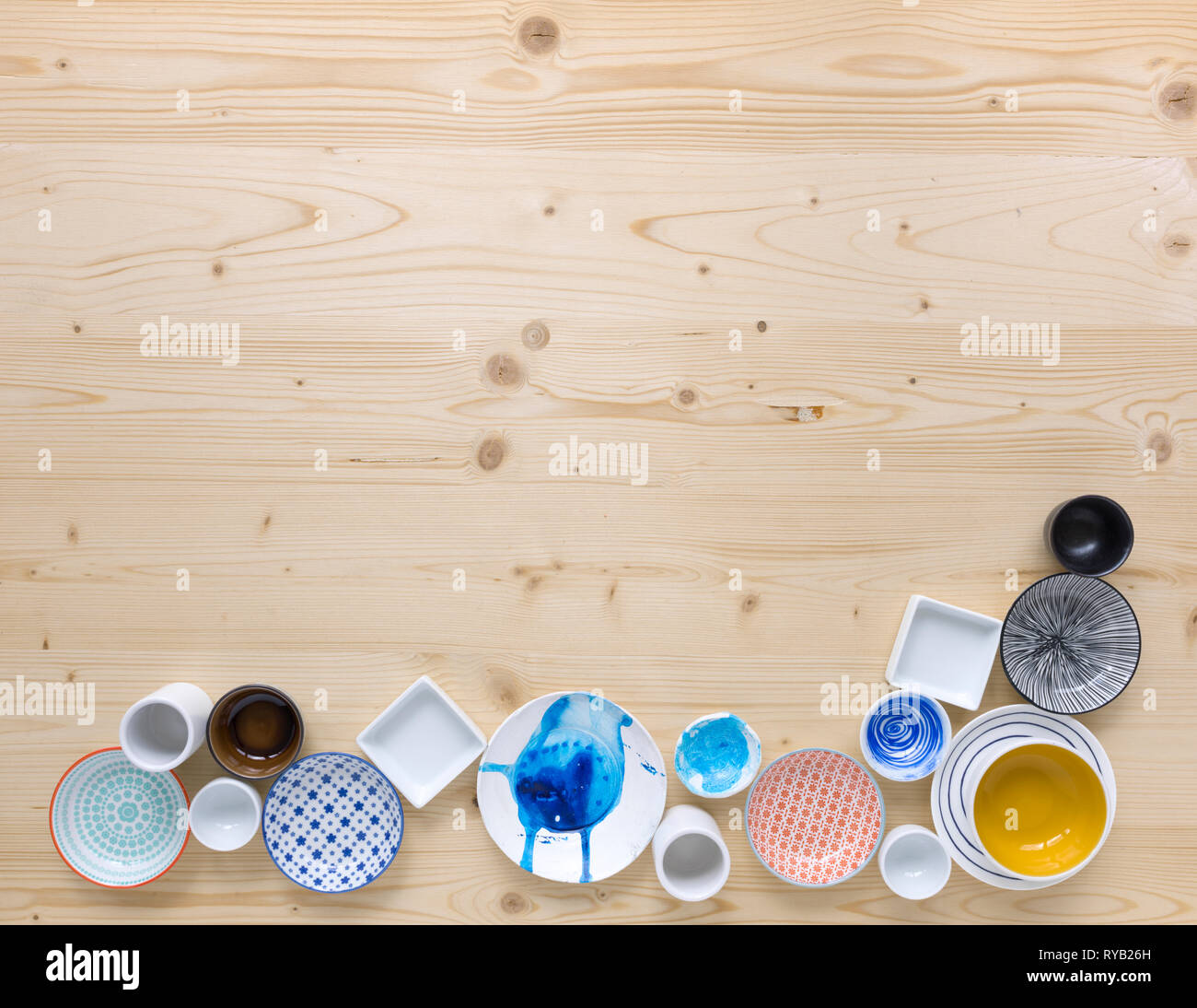 different kinds of modern colourful and white crockery on light wood ...
