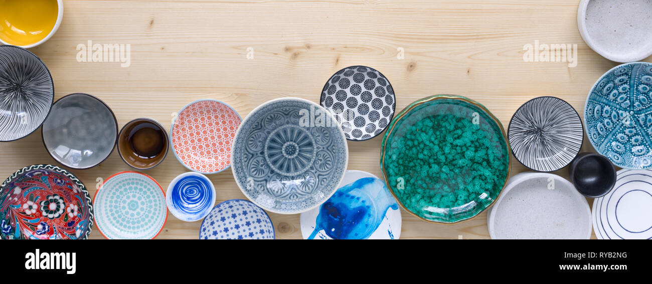 different kinds of modern colourful and white crockery on light wood ...
