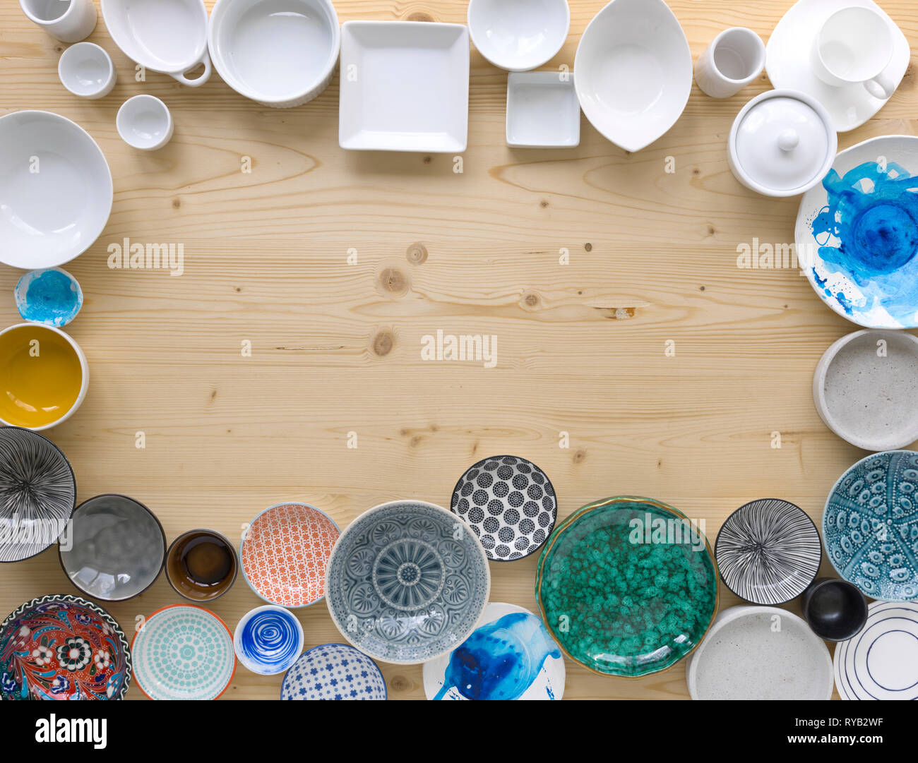 different kinds of modern colourful and white crockery on light wood ...