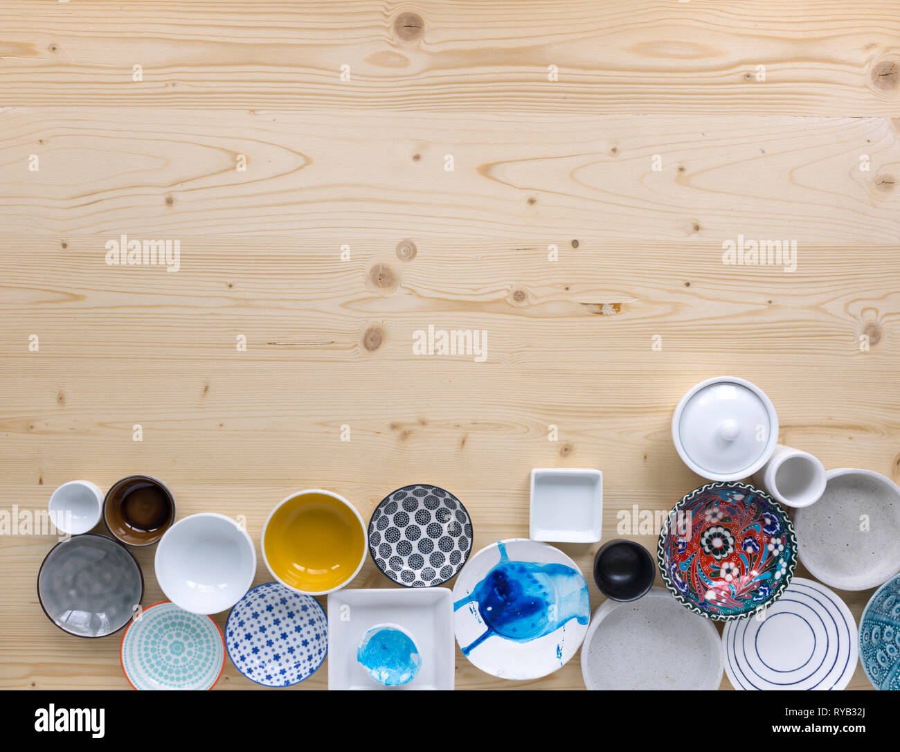 different kinds of modern colourful and white crockery on light wood ...