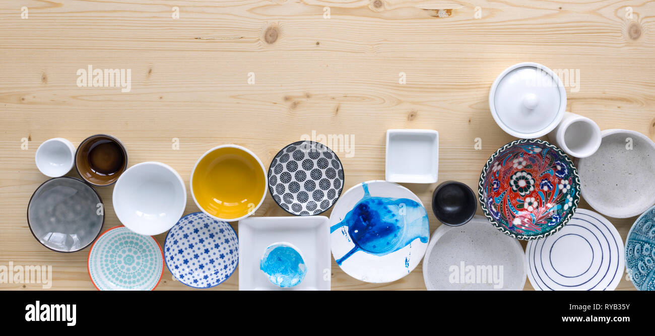 different kinds of modern colourful and white crockery on light wood ...