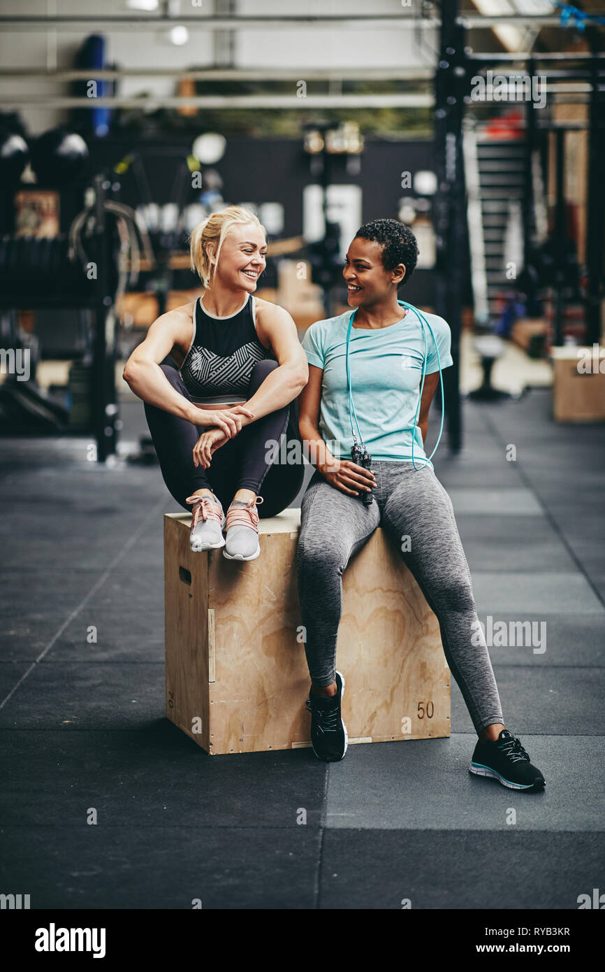 Two fit young female friends in sportswear laughing after a workout ...