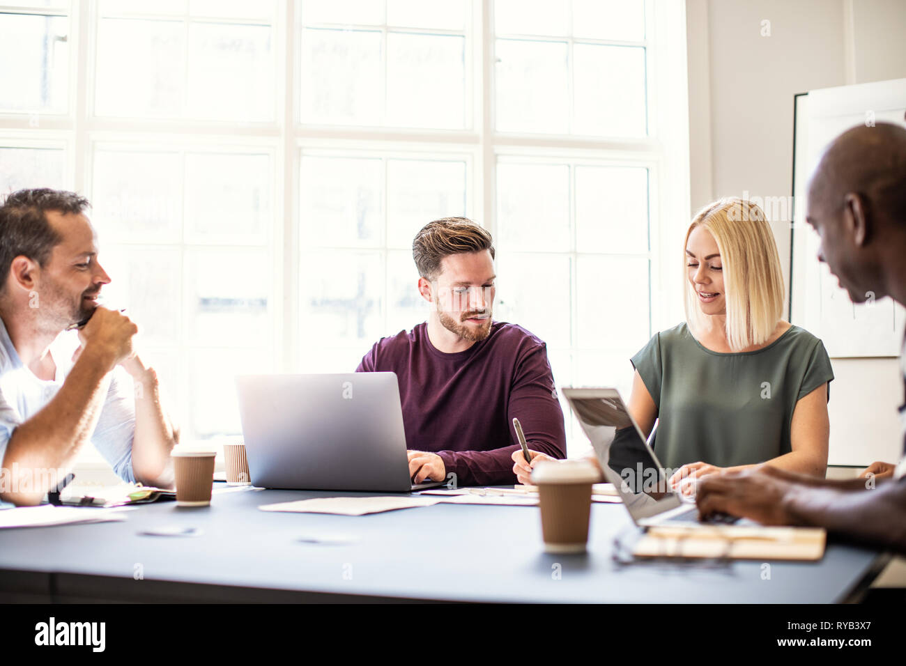 Diverse group of designers discussing a project together while sitting ...