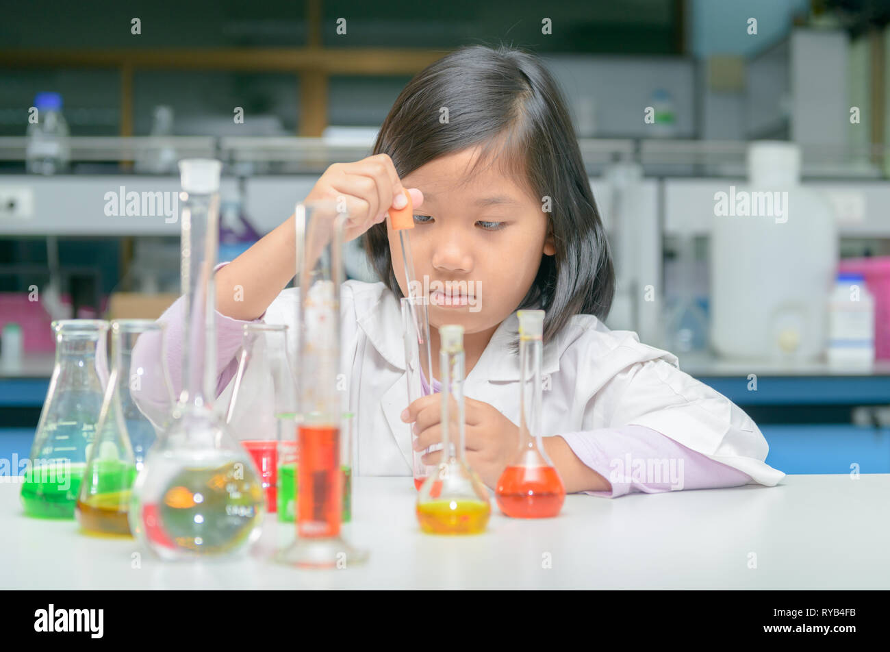little scientist in lab coat making experiment with test tube in ...