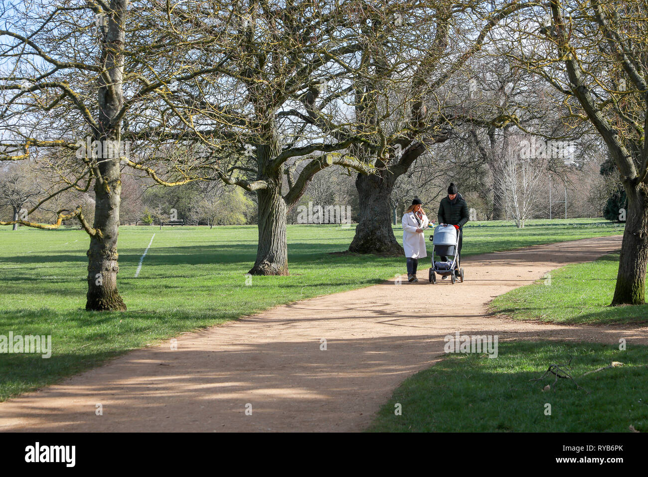 Mother and father walking with a buggy stroller pram on a gravel path ...