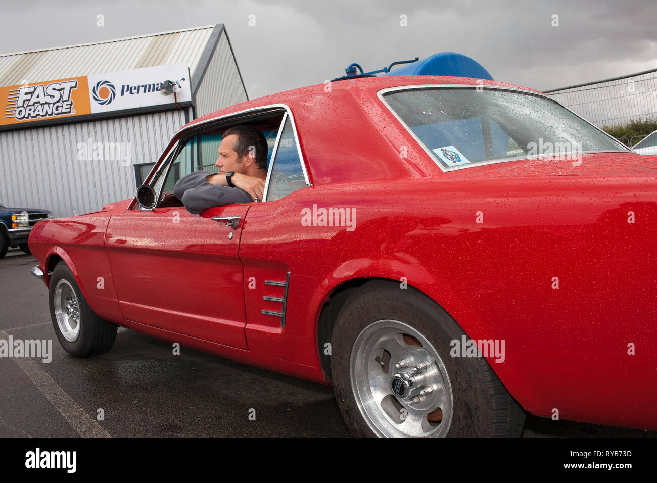 A man leans out of a classic red car Stock Photo - Alamy