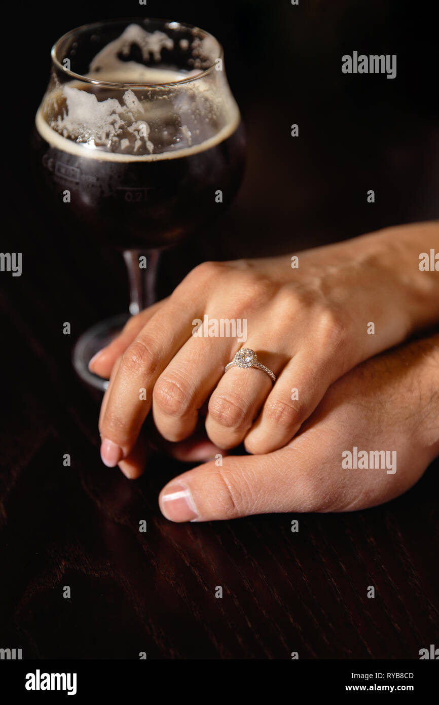 Real life proposal: Couple holding hands in a pub with a glass of beer ...